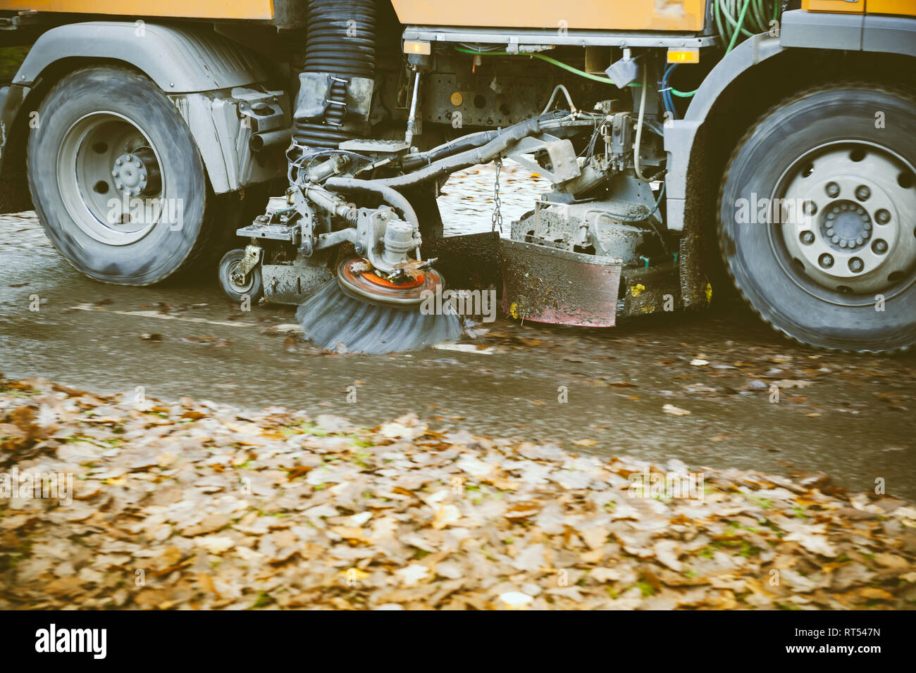 Wheels detail of in motion orange street sweeper truck on the street ...