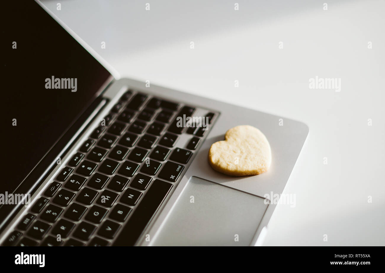 Heart shaped cookie snack on modern aluminium professional laptop ...