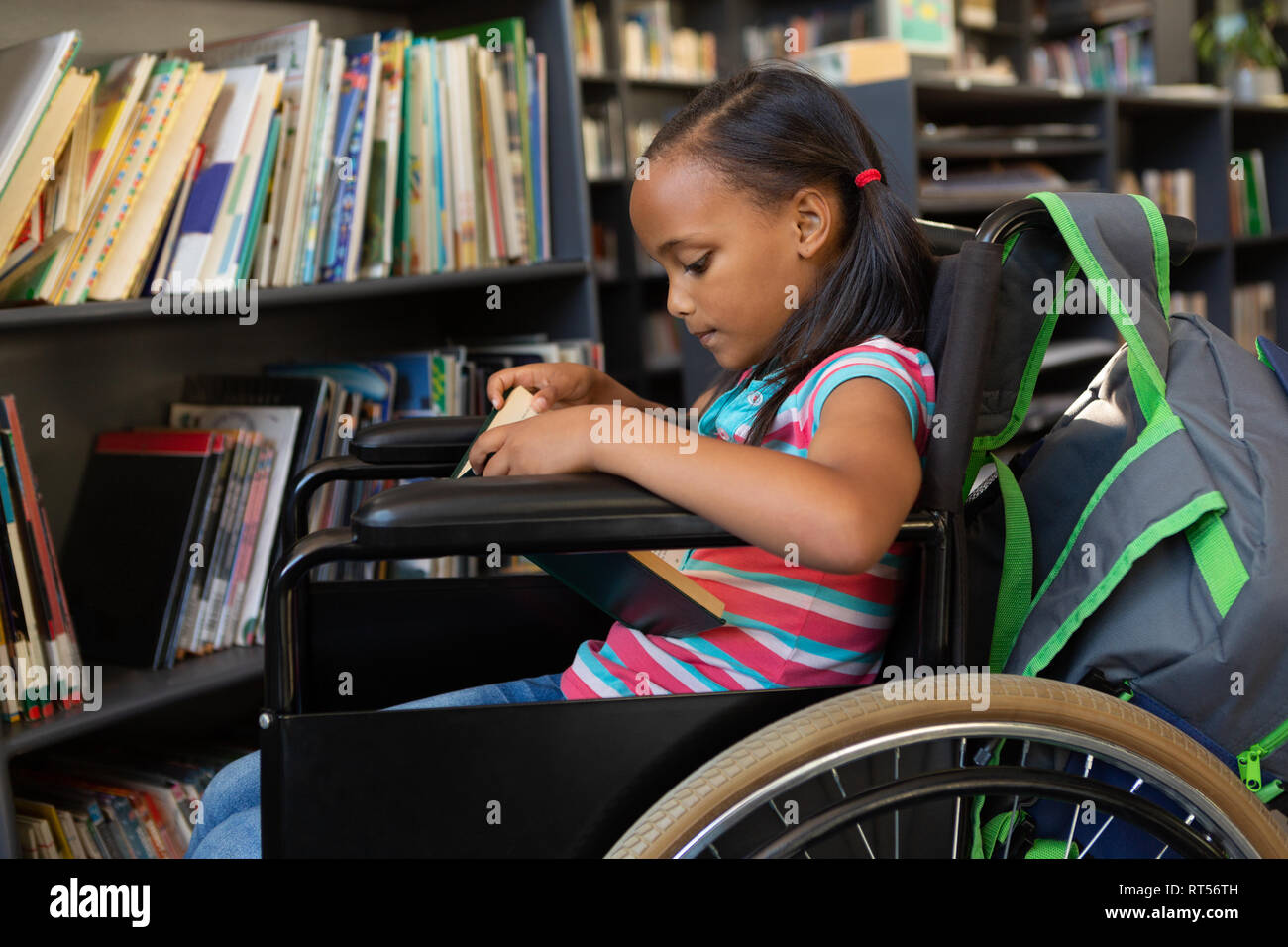 Disabled schoolgirl reading a book in the classroom Stock Photo - Alamy