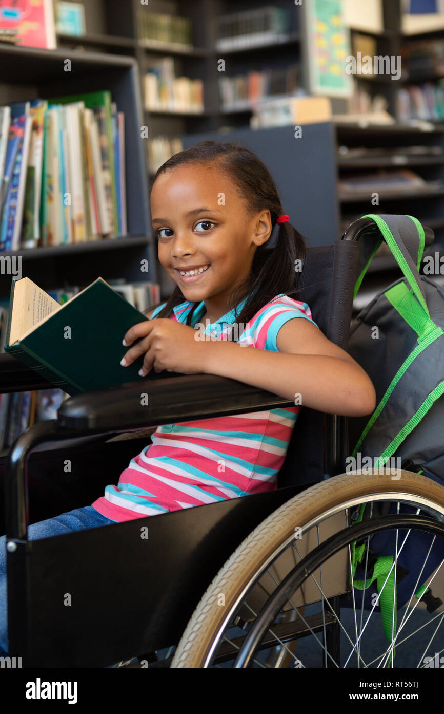 Disabled schoolgirl reading a book in the classroom Stock Photo - Alamy