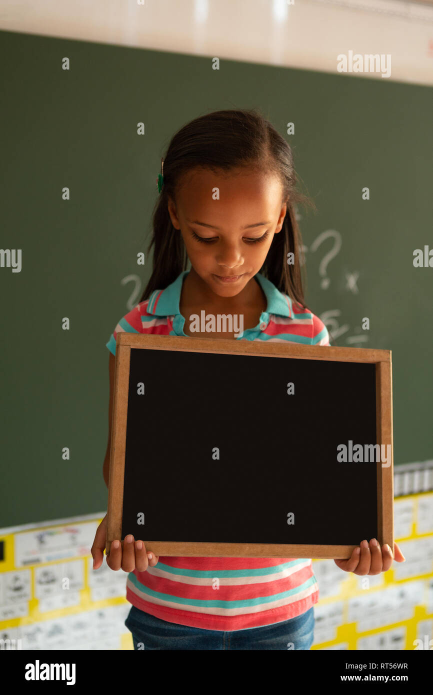 Schoolgirl holding a slate in the classroom Stock Photo - Alamy