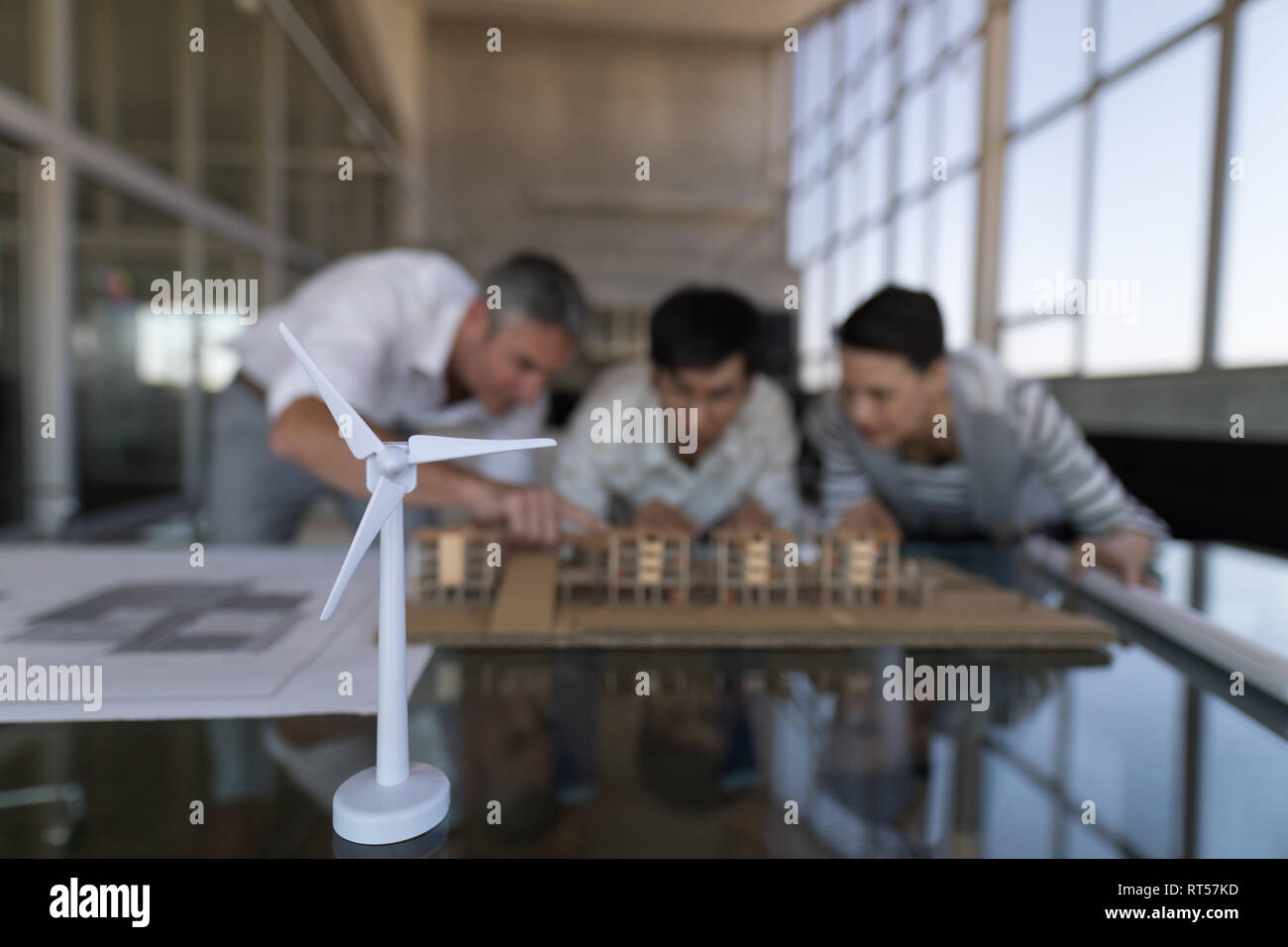 Windmill on a table while business colleagues looking at house model ...