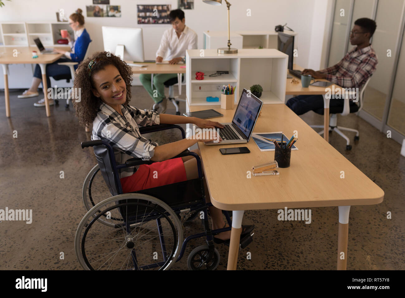 Disabled female executive using laptop at desk Stock Photo - Alamy
