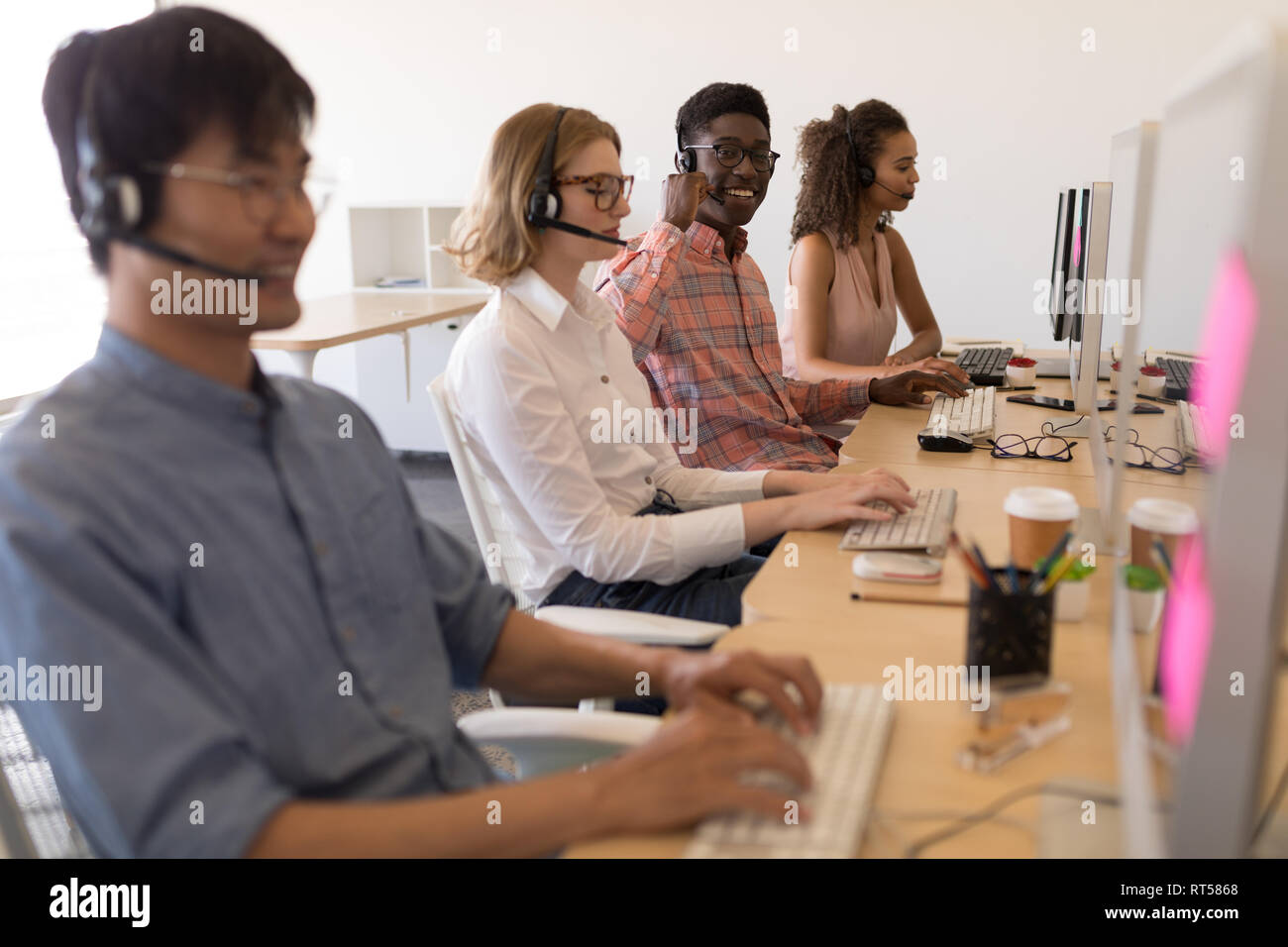 Executives working on personal computer while talking on headset in ...