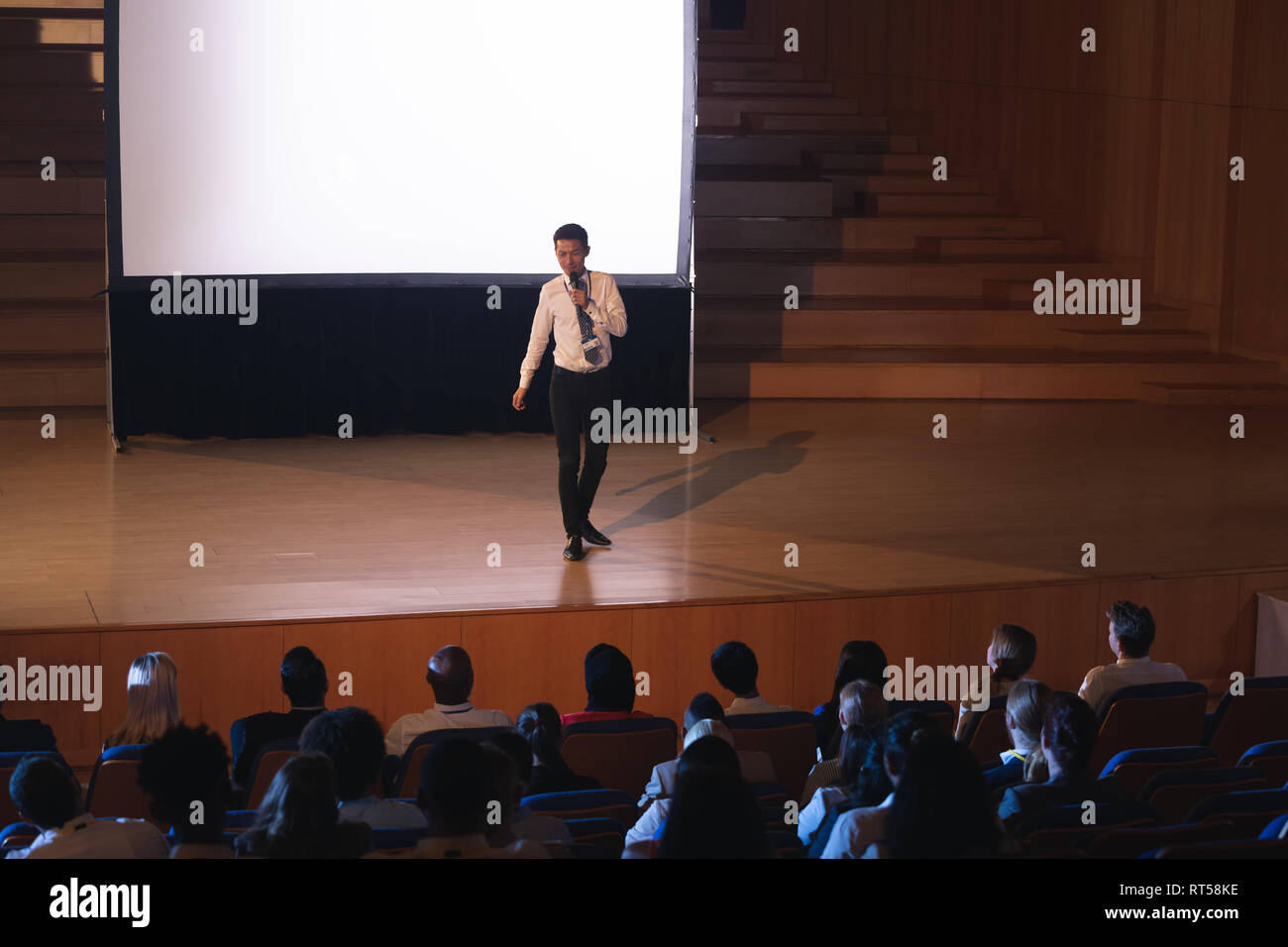 Businessman standing and giving presentation in auditorium Stock Photo ...