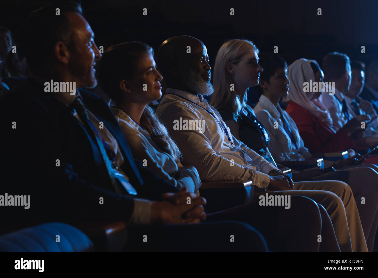 Business colleagues sitting and watching presentation with audience ...