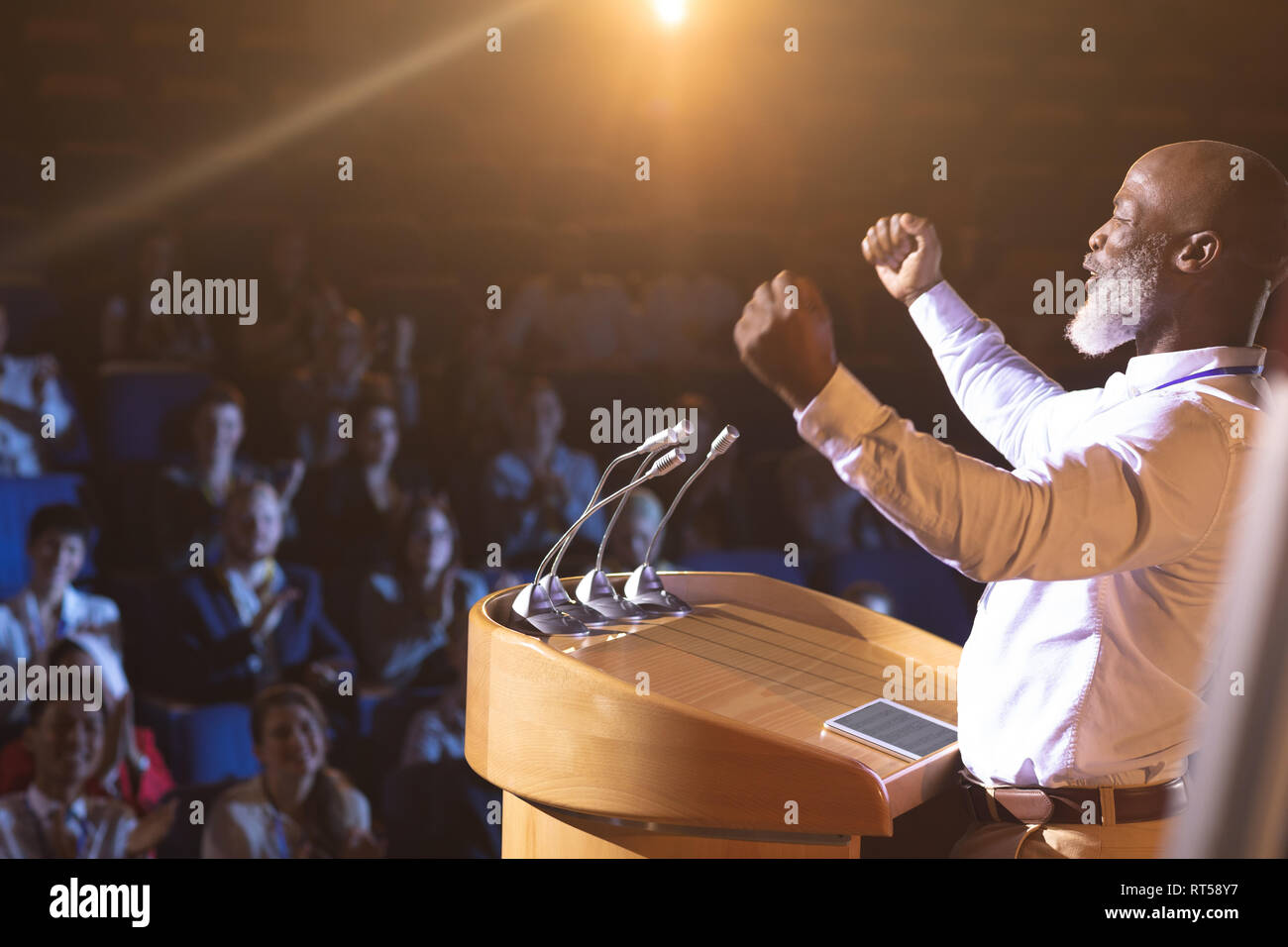 Businessman standing near podium and giving speech to the audience in ...