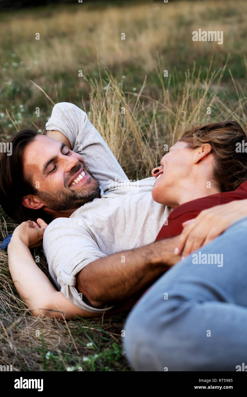 Happy couple cuddling, lying on a meadow Stock Photo - Alamy