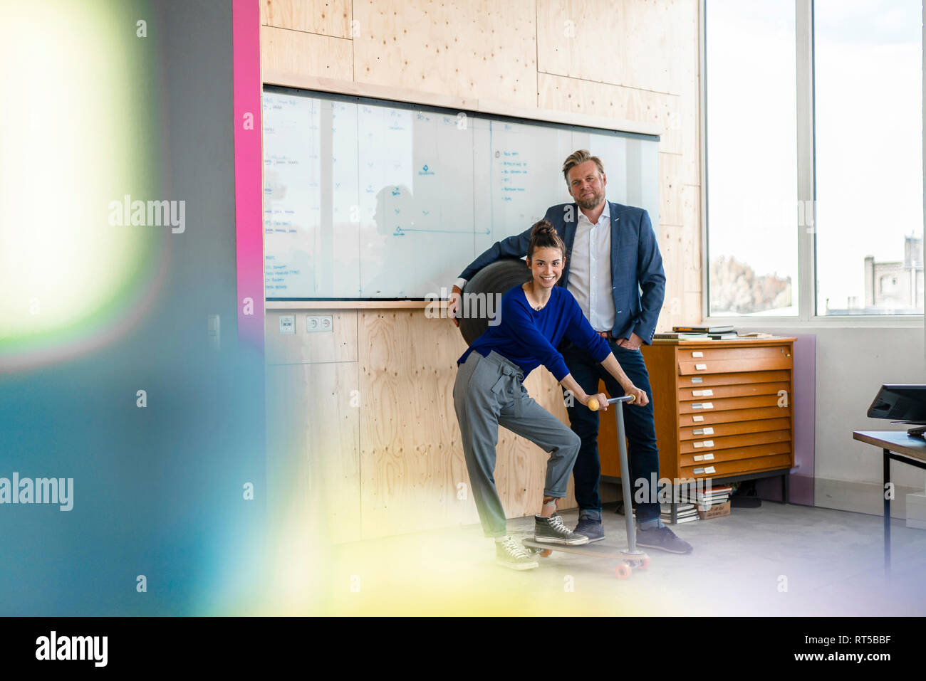 Mature man and his assistent with scooter, standing in office in front ...