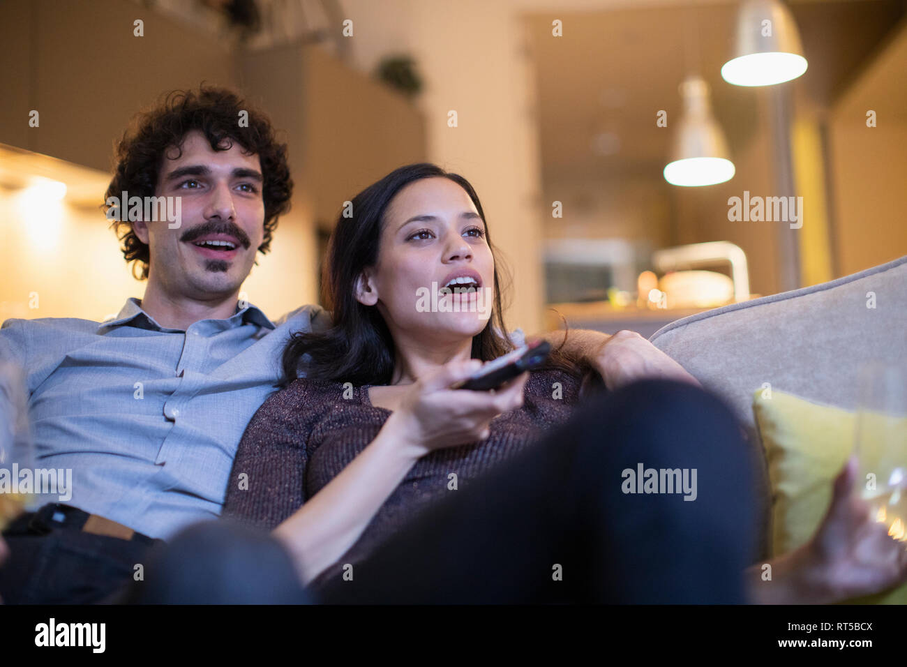 Couple watching TV on sofa Stock Photo - Alamy