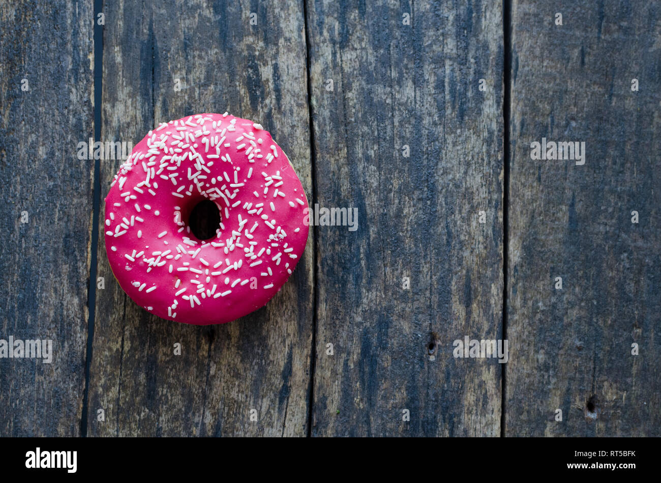 Donuts with pink icing on wooden background with place for text ...