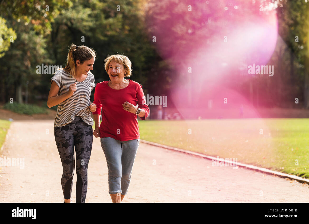 Granddaughter and grandmother having fun, jogging together in the park ...