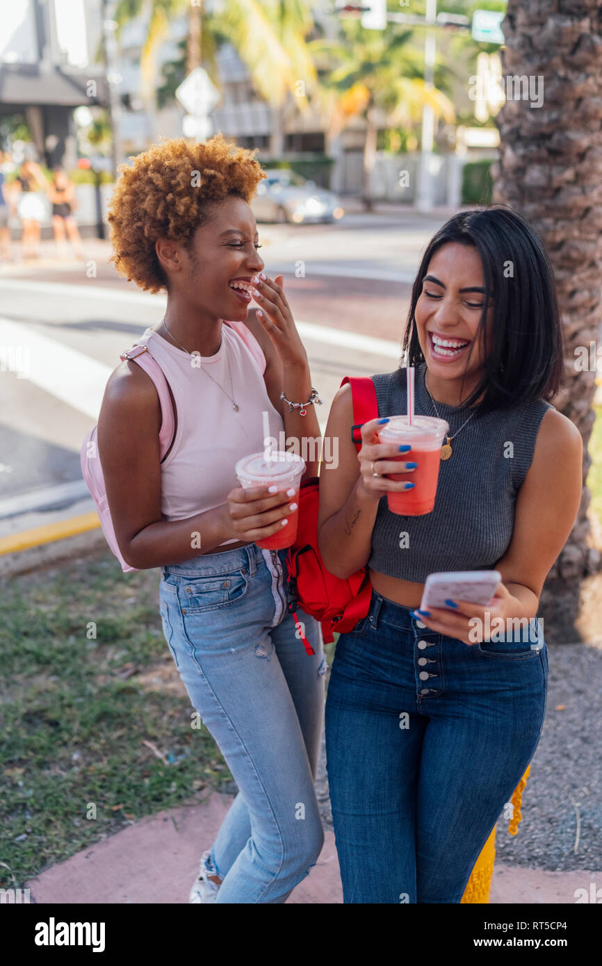 USA, Florida, Miami Beach, two happy female friends with cell phone and ...