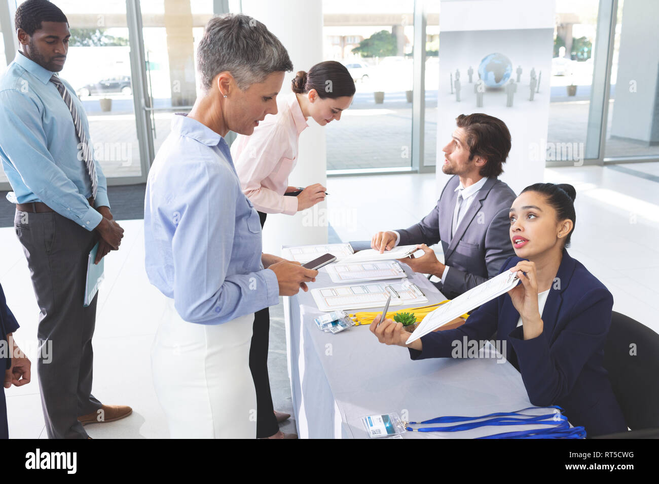 Business people checking in at conference registration table Stock ...