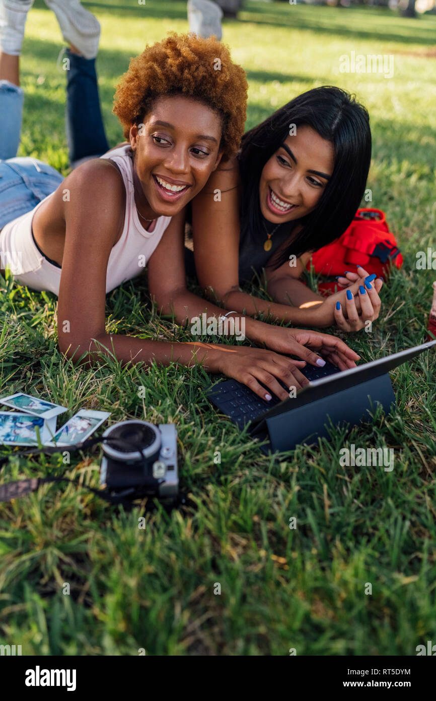 Two happy female friends relaxing in a park using a tablet Stock Photo ...