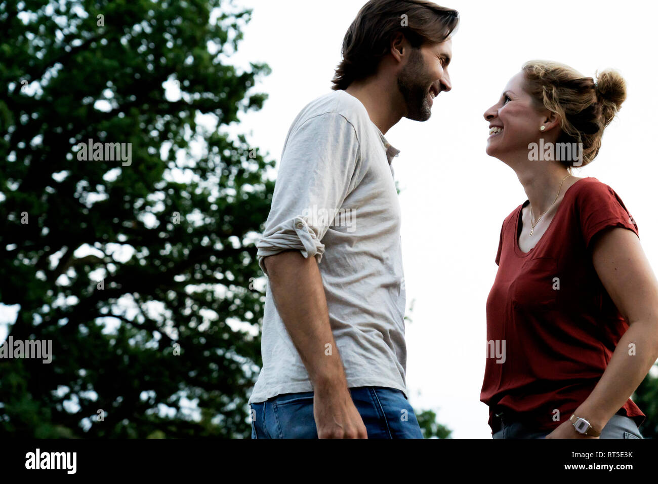 Happy couple in nature, standing face to face, smiling at each other ...