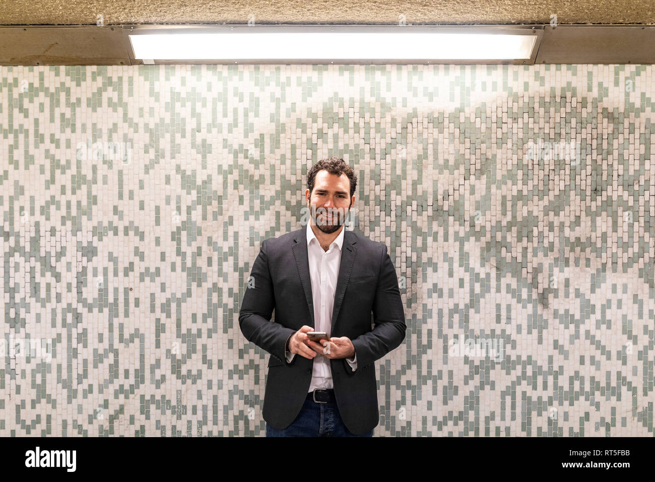 UK, London, portrait of smiling businessman in an a subway passage ...