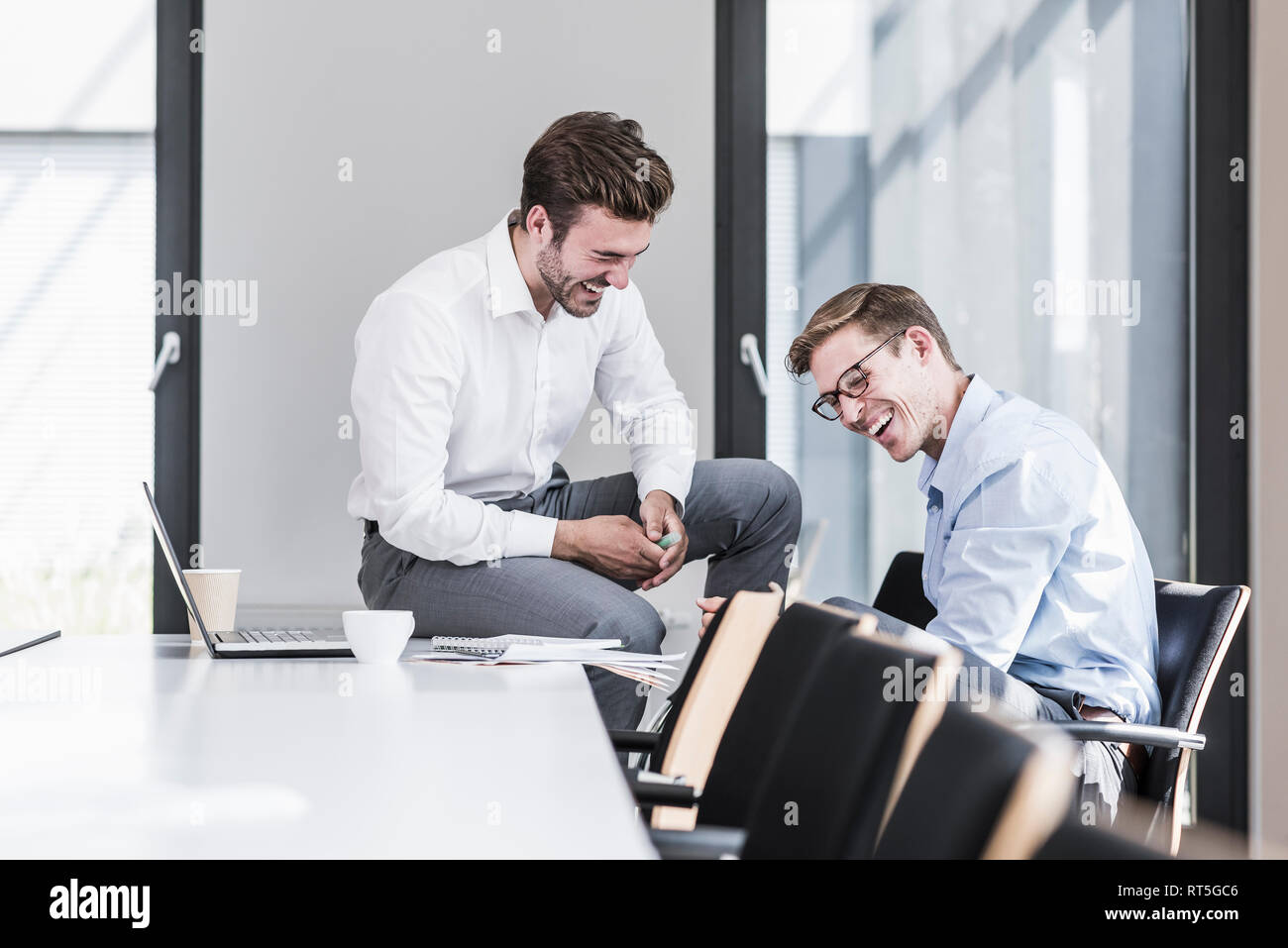 Two laughing colleagues in office Stock Photo - Alamy
