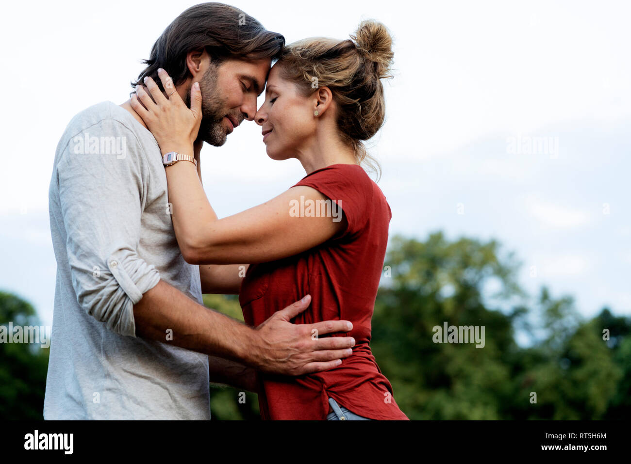 Happy couple in nature, standing face to face, caressing each other ...