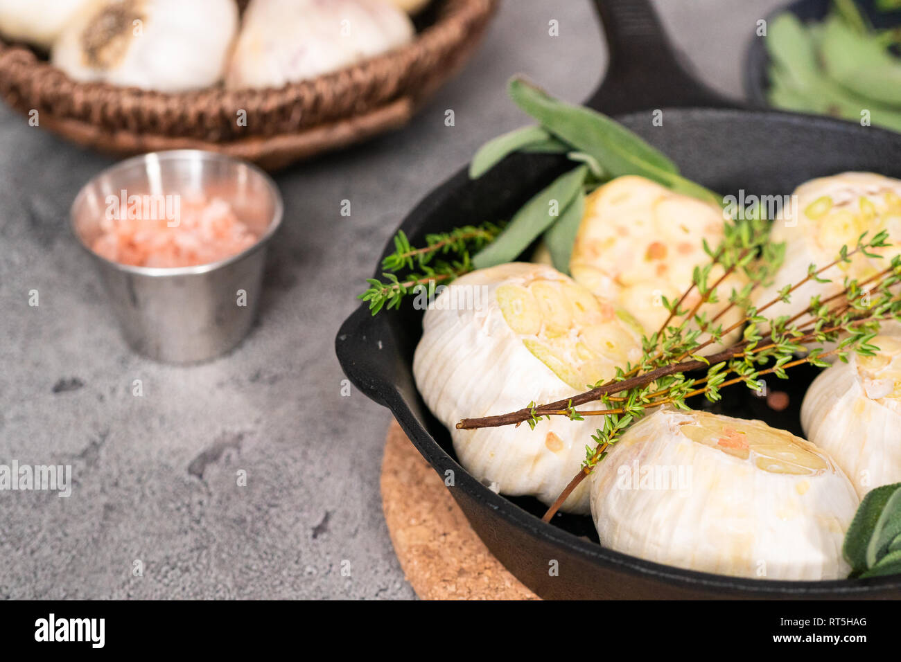 Raw garlic heads with fresh spices in cast iron skillet for preparing ...