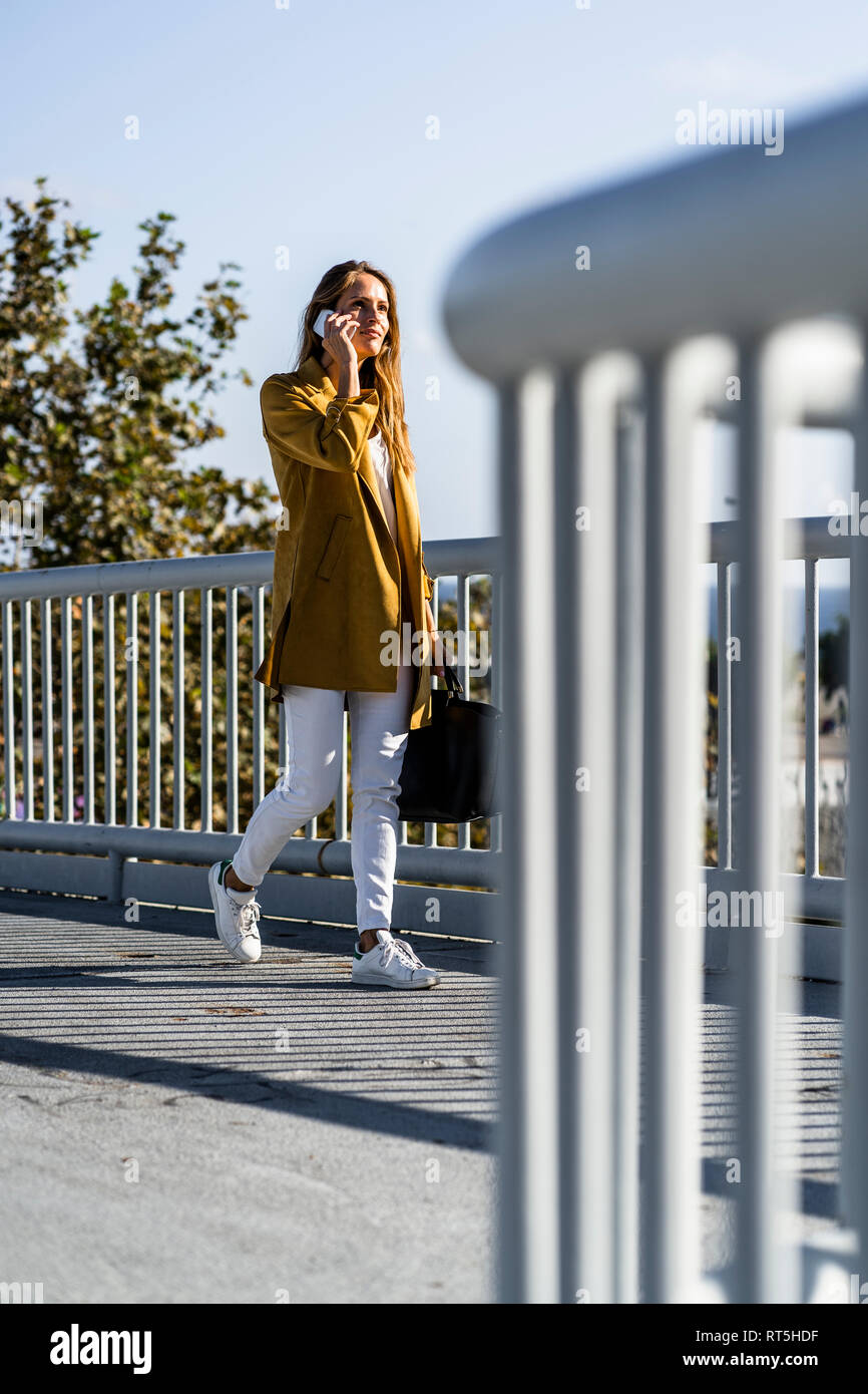 Woman on cell phone walking on a bridge Stock Photo - Alamy
