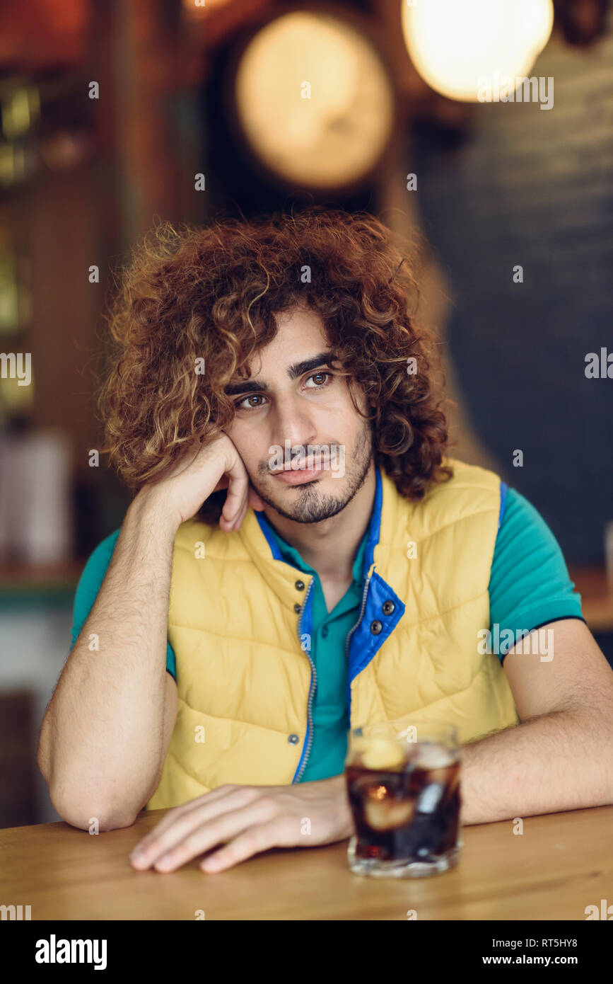 Portrait of young man with beard and curly hair waiting in a pub Stock ...