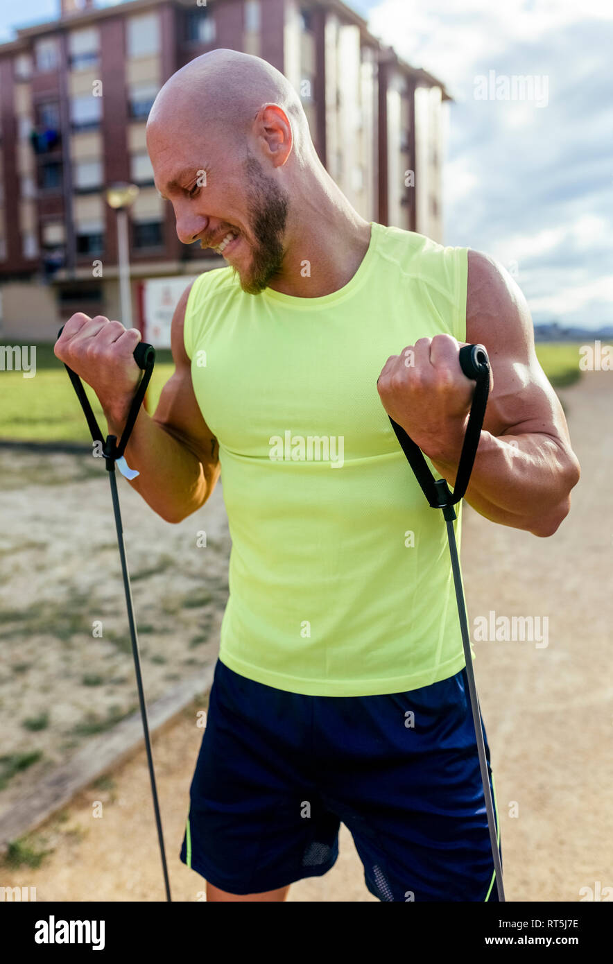 Muscular man exercising with expander outdoors Stock Photo - Alamy