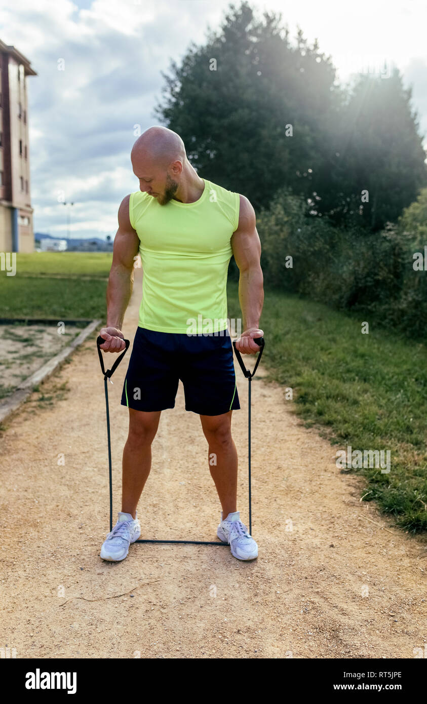 Muscular man exercising with expander outdoors Stock Photo - Alamy