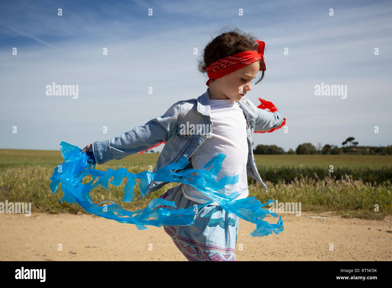 Girls playing with ribbon on path in remote landscape Stock Photo - Alamy