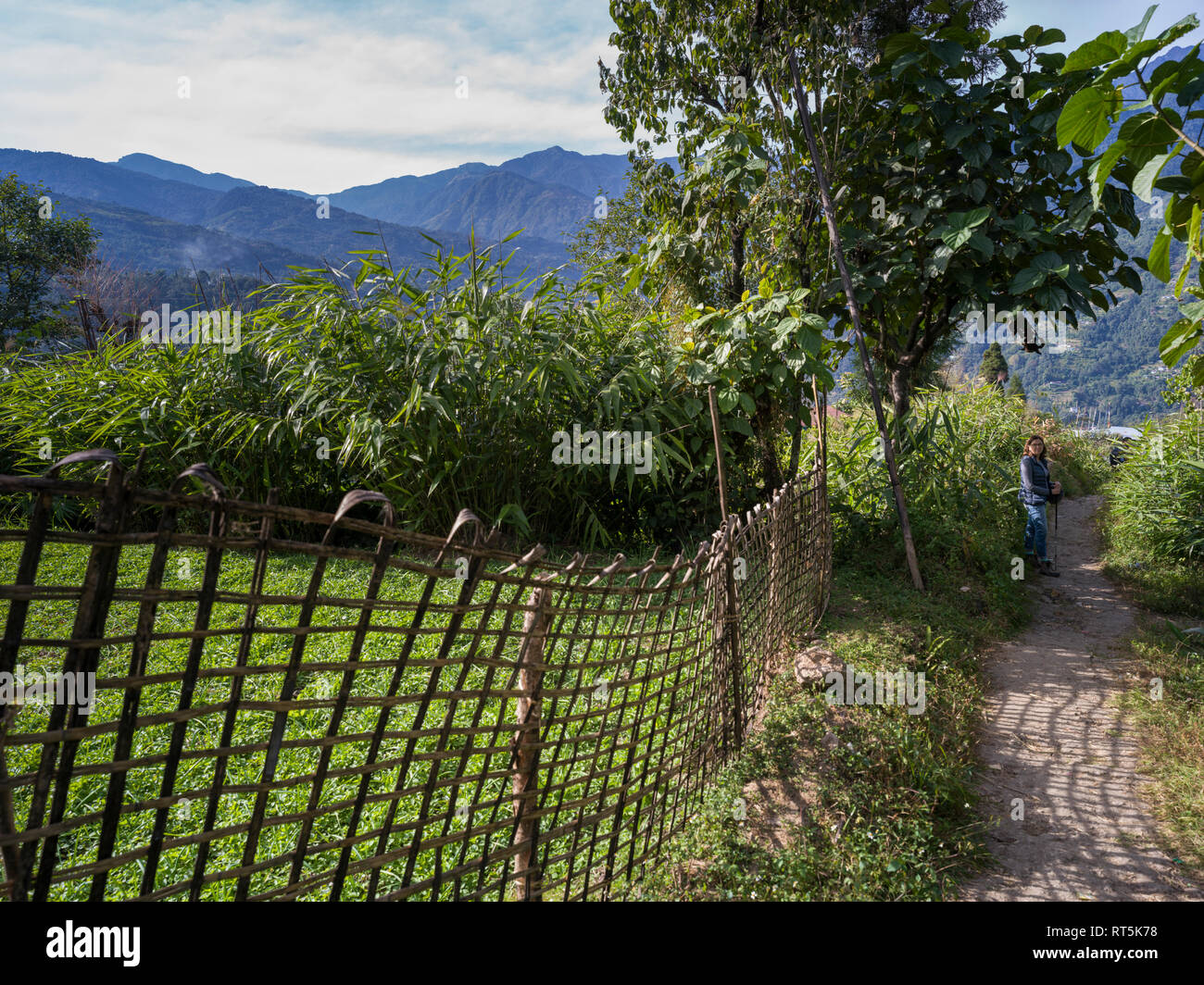 Female tourist standing on a path with mountain range in the background ...