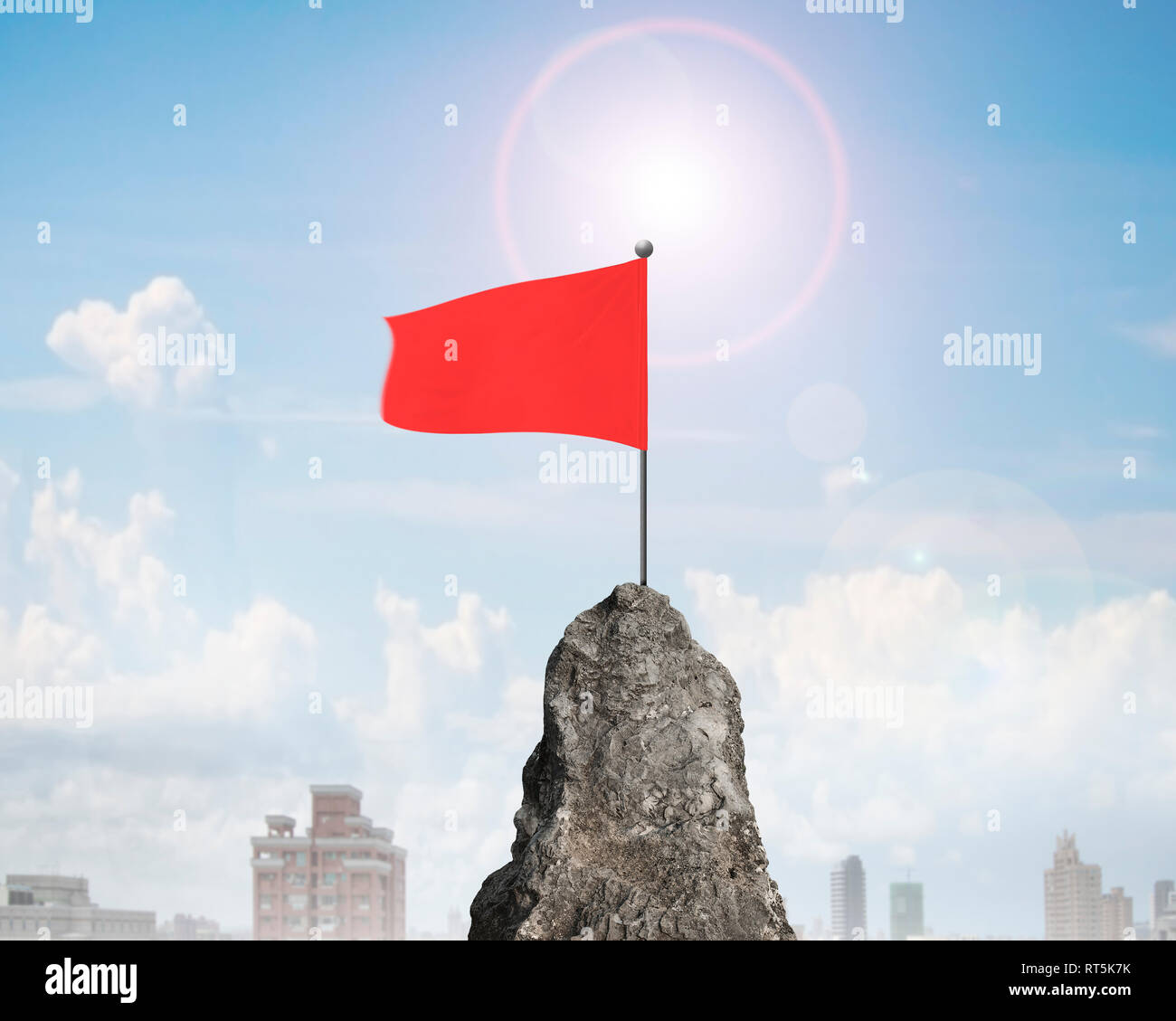 Red wavy flag on top of rocky mountain peak with sunlight and clouds in ...