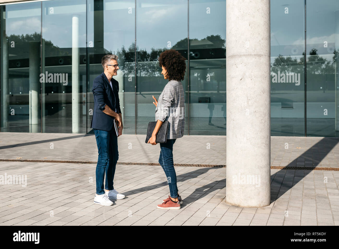 Two colleagues talking outside office building Stock Photo - Alamy