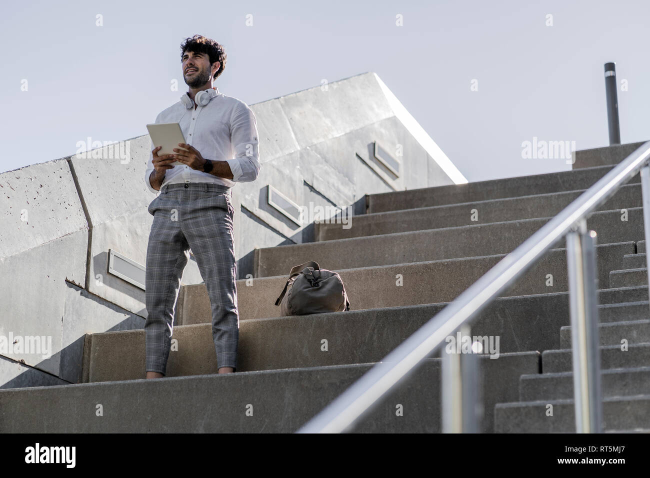 Young man standing on stairs outdoors holding tablet Stock Photo - Alamy