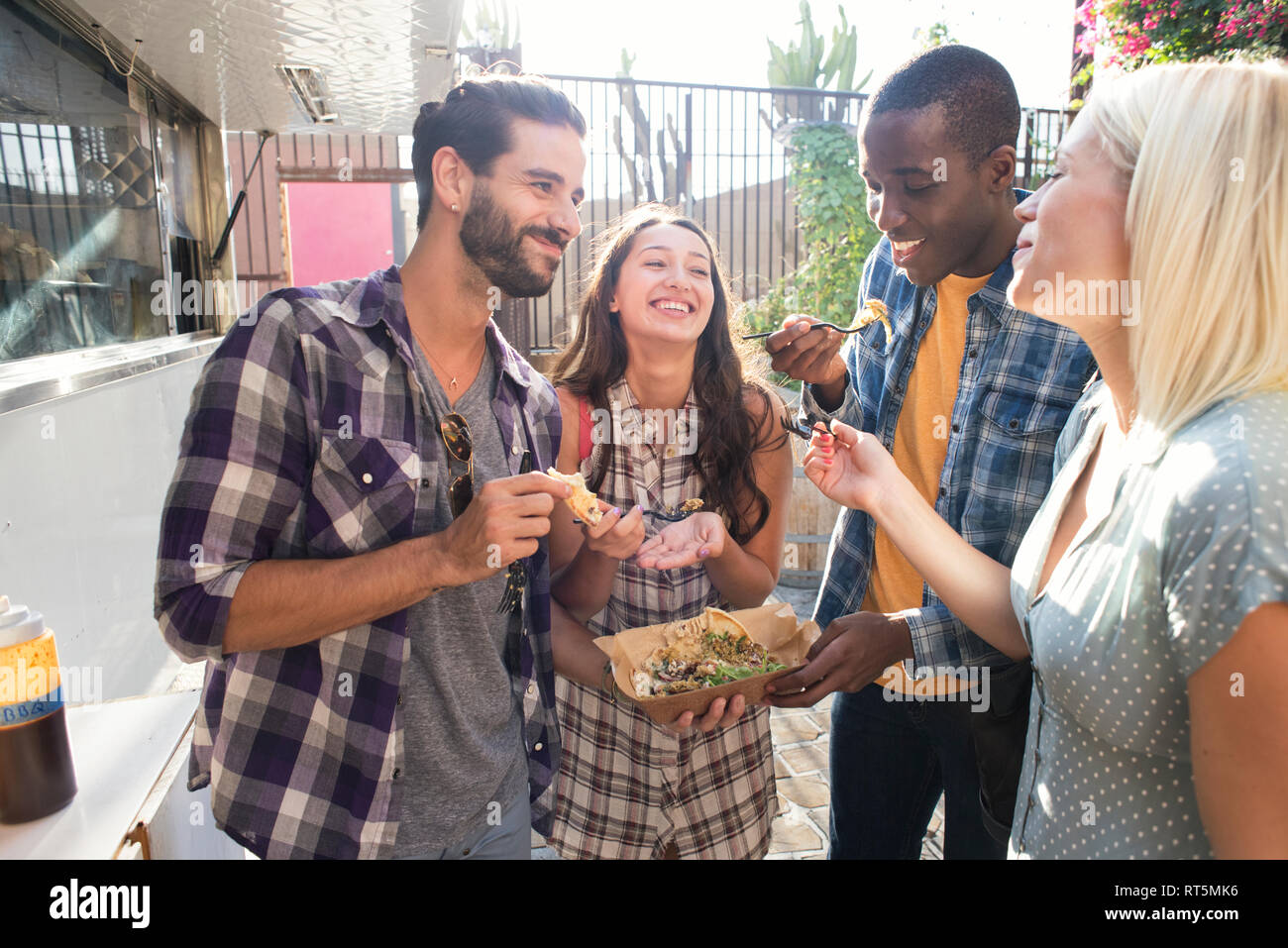 Happy friends sharing takeaway food outdoors Stock Photo - Alamy