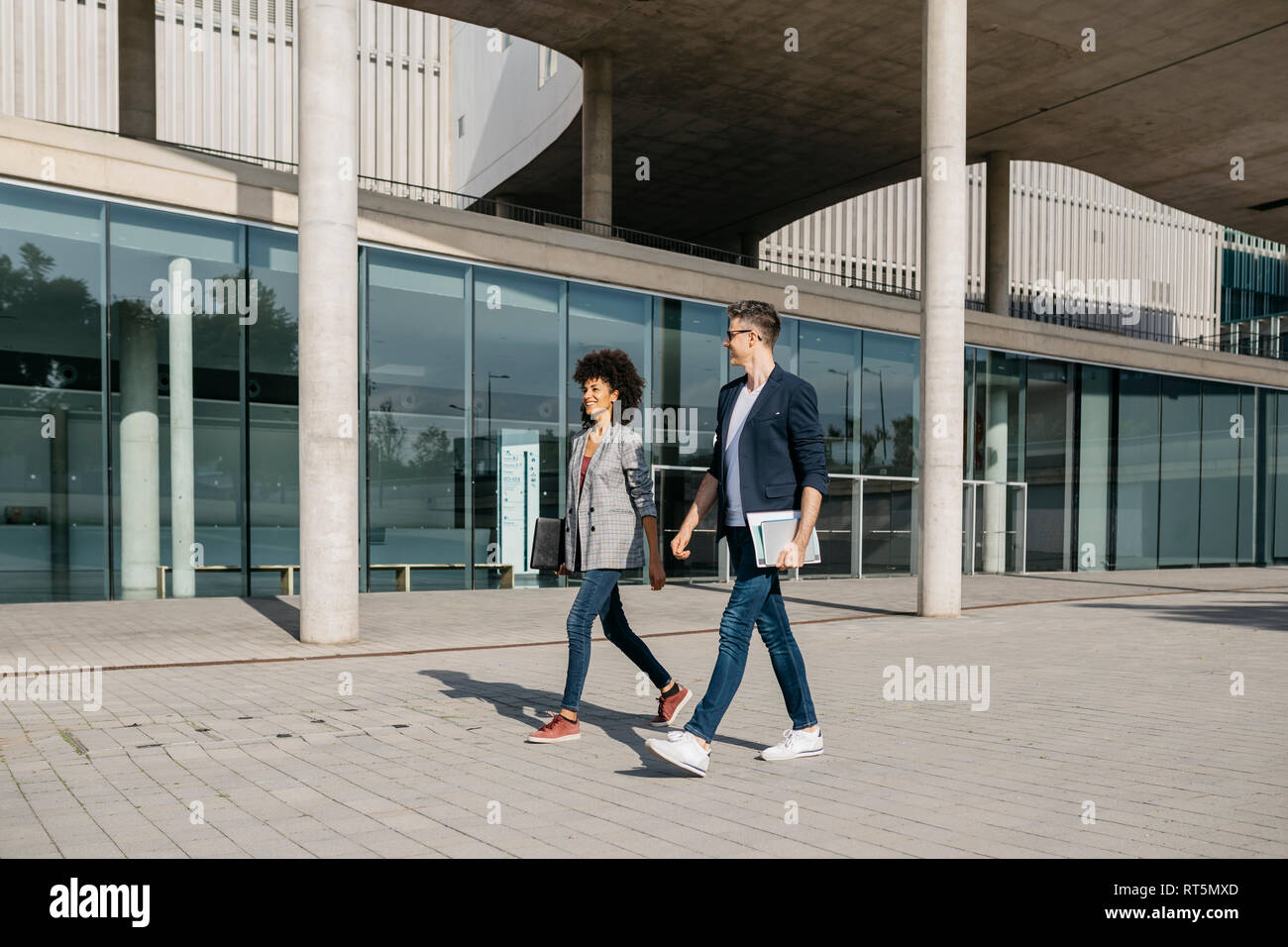 Two colleagues walking outside office building Stock Photo - Alamy