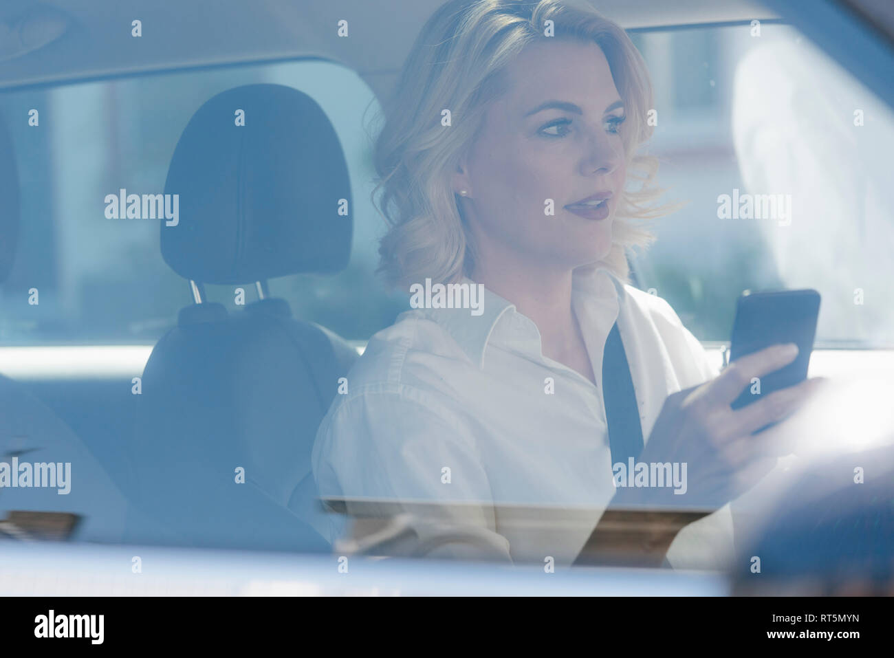 Businesswoman using cell phone while driving car Stock Photo - Alamy