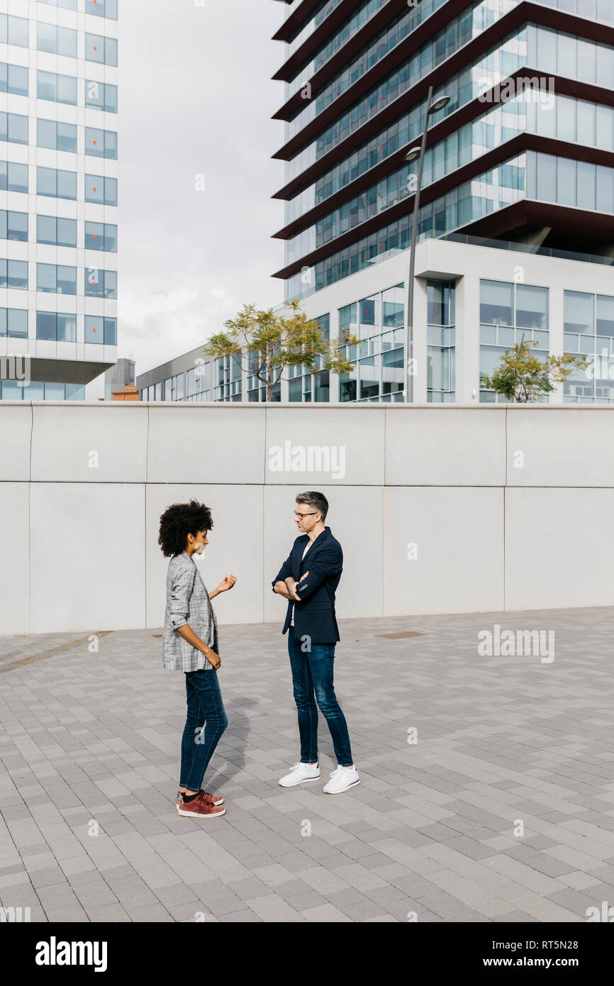 Two colleagues talking outside office building Stock Photo - Alamy