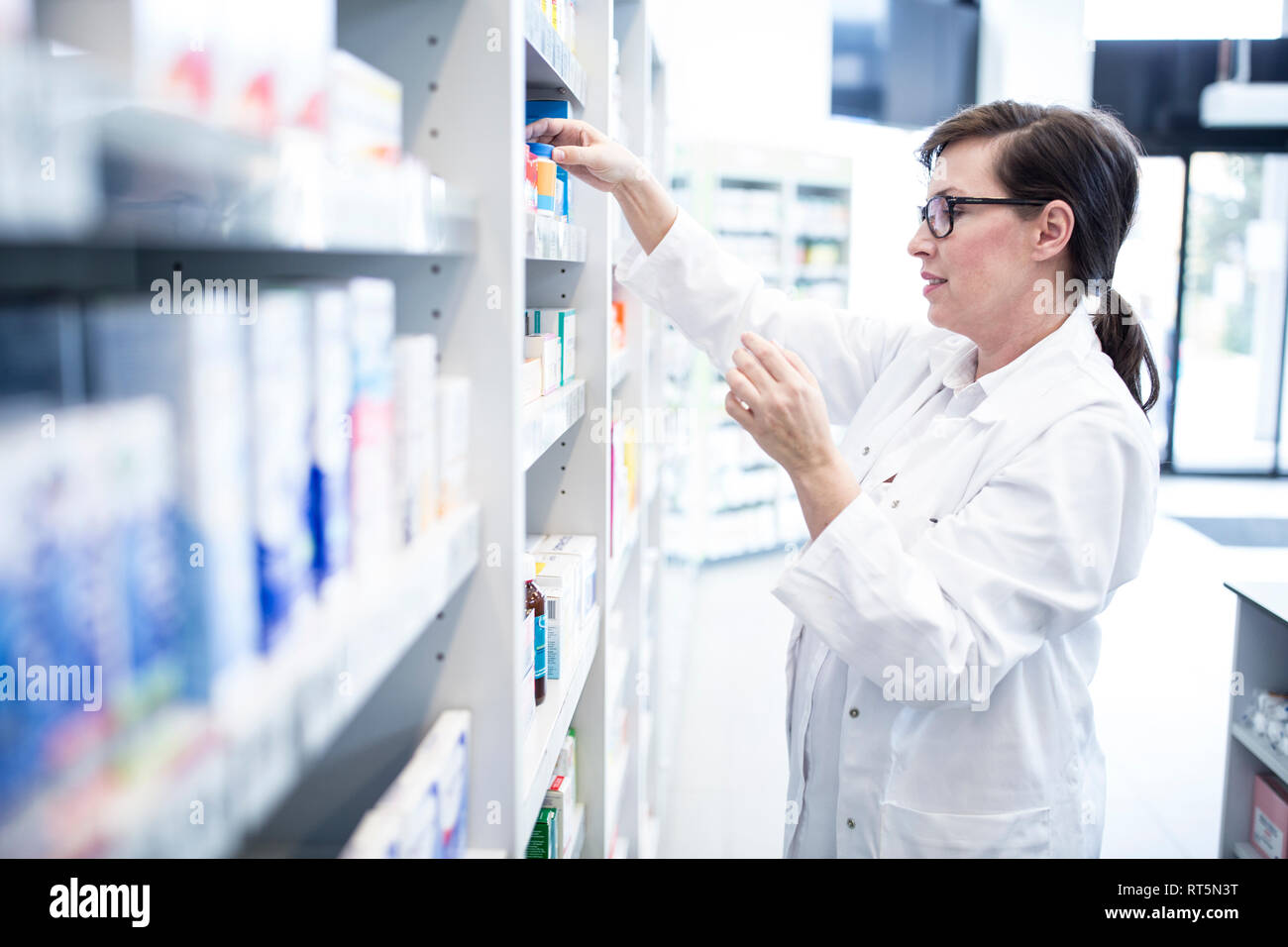 Pharmacist sorting medicine at shelf in pharmacy Stock Photo - Alamy