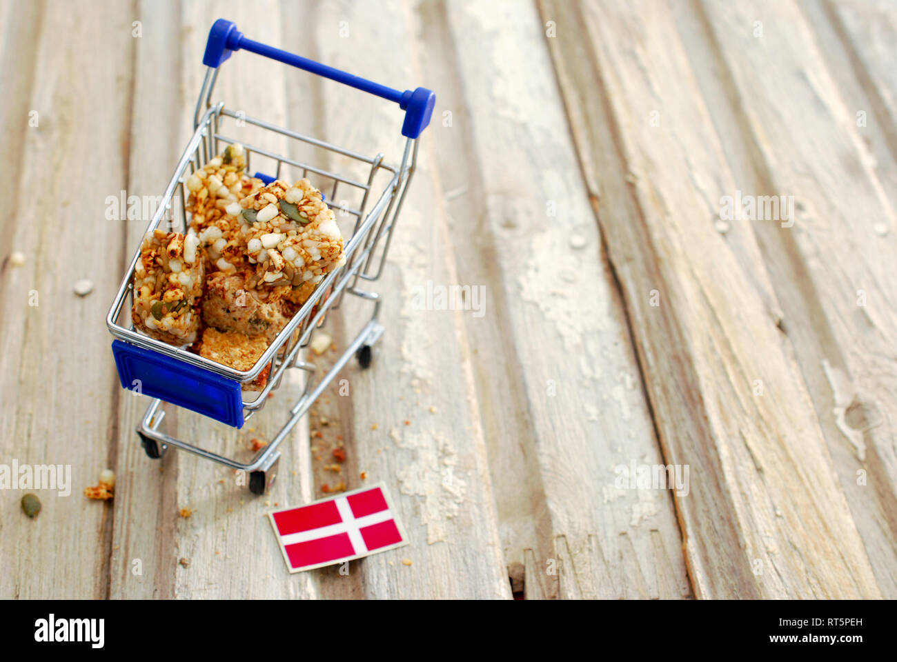 shopping cart with cereal bar pieces and flag od denmark on wood ...
