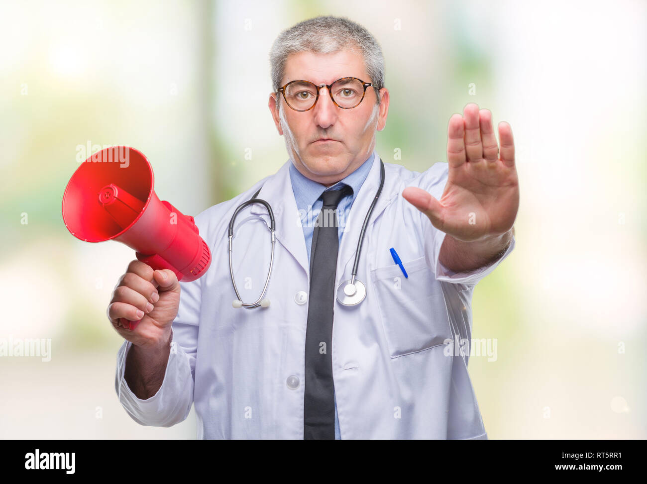 Handsome senior doctor man yelling through megaphone over isolated ...