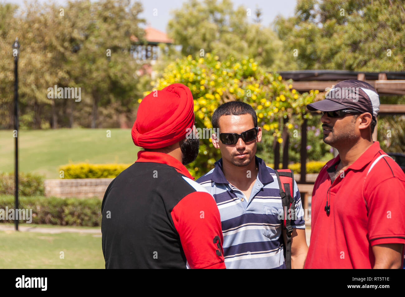 A trio of Indian men involved in a conversation on a bright sunny ...