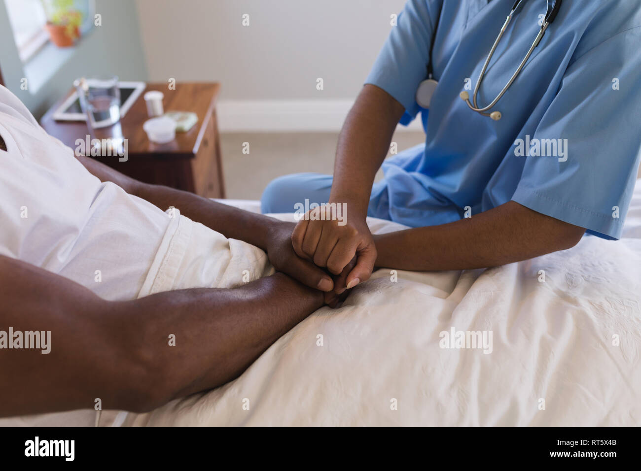 Female doctor consoling senior man in bedroom at home Stock Photo - Alamy