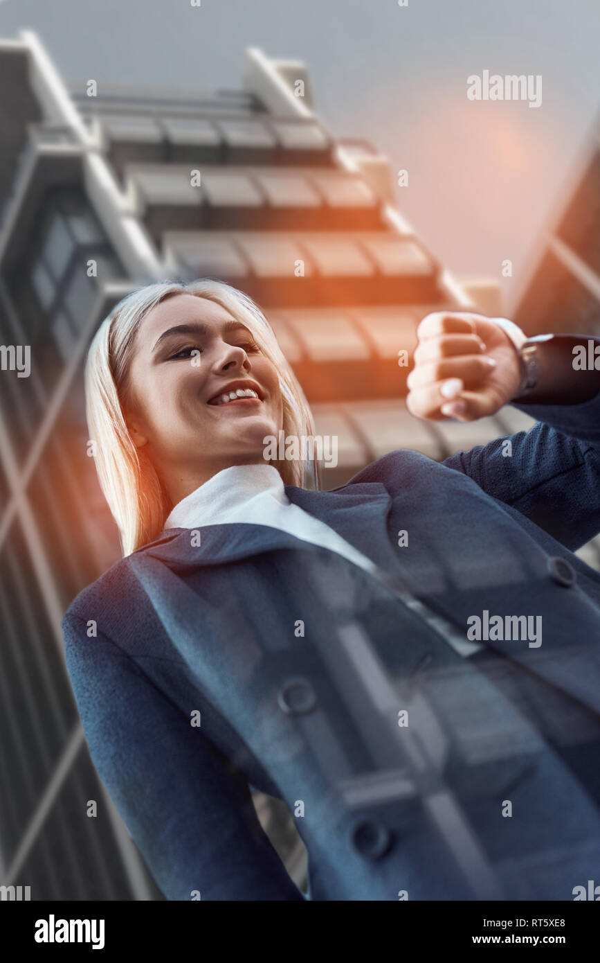 What time is it? Cheerful business woman in suit looking at her watch ...