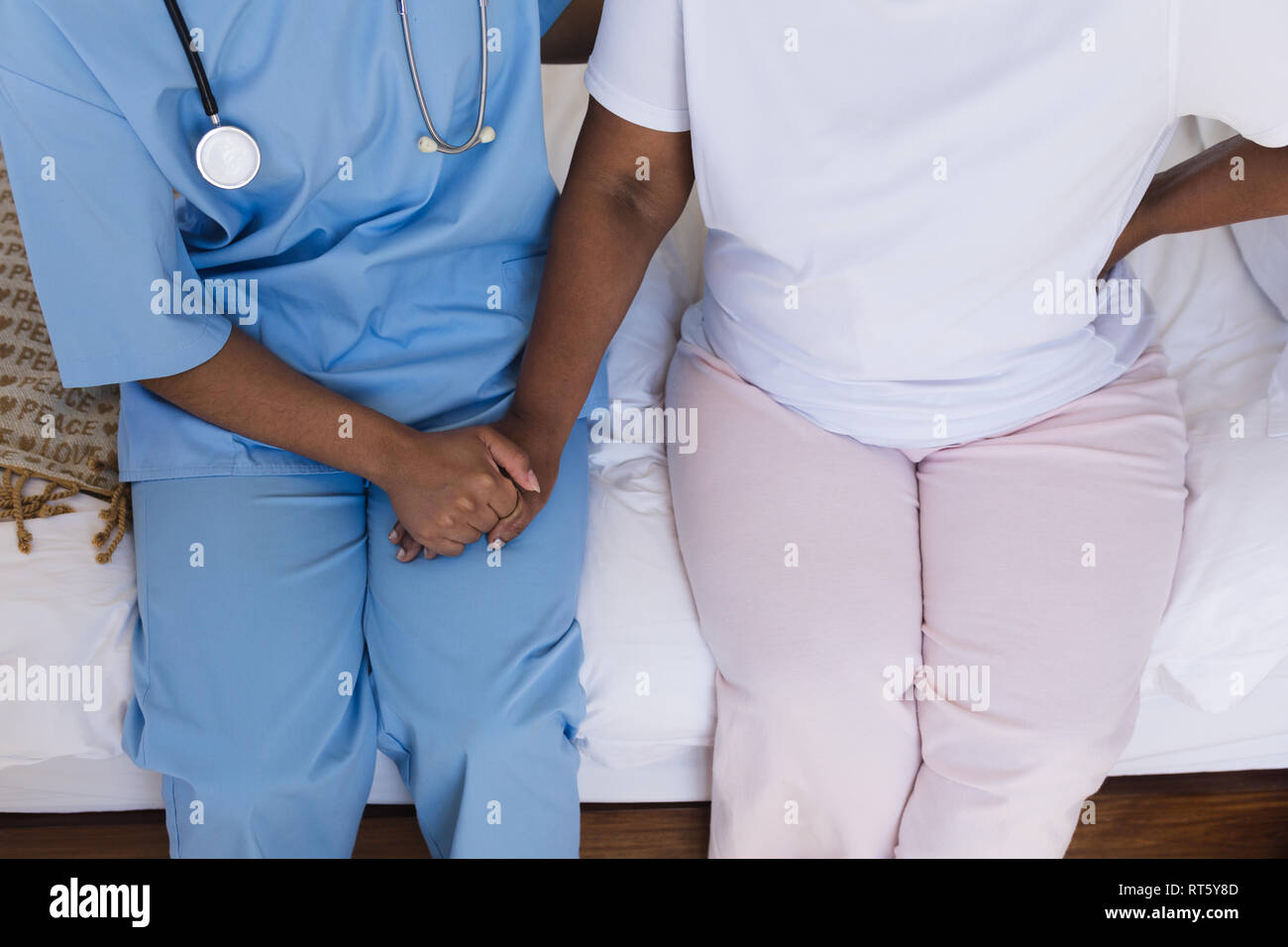 Female doctor consoling senior woman in bedroom at home Stock Photo - Alamy