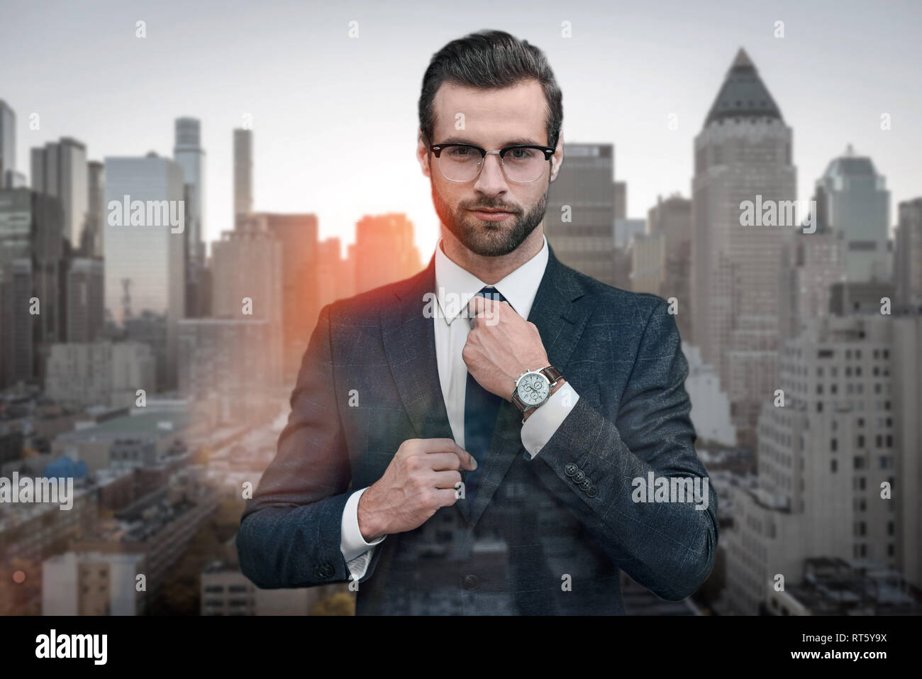 Perfect look! Confident business expert in glasses adjusting necktie ...
