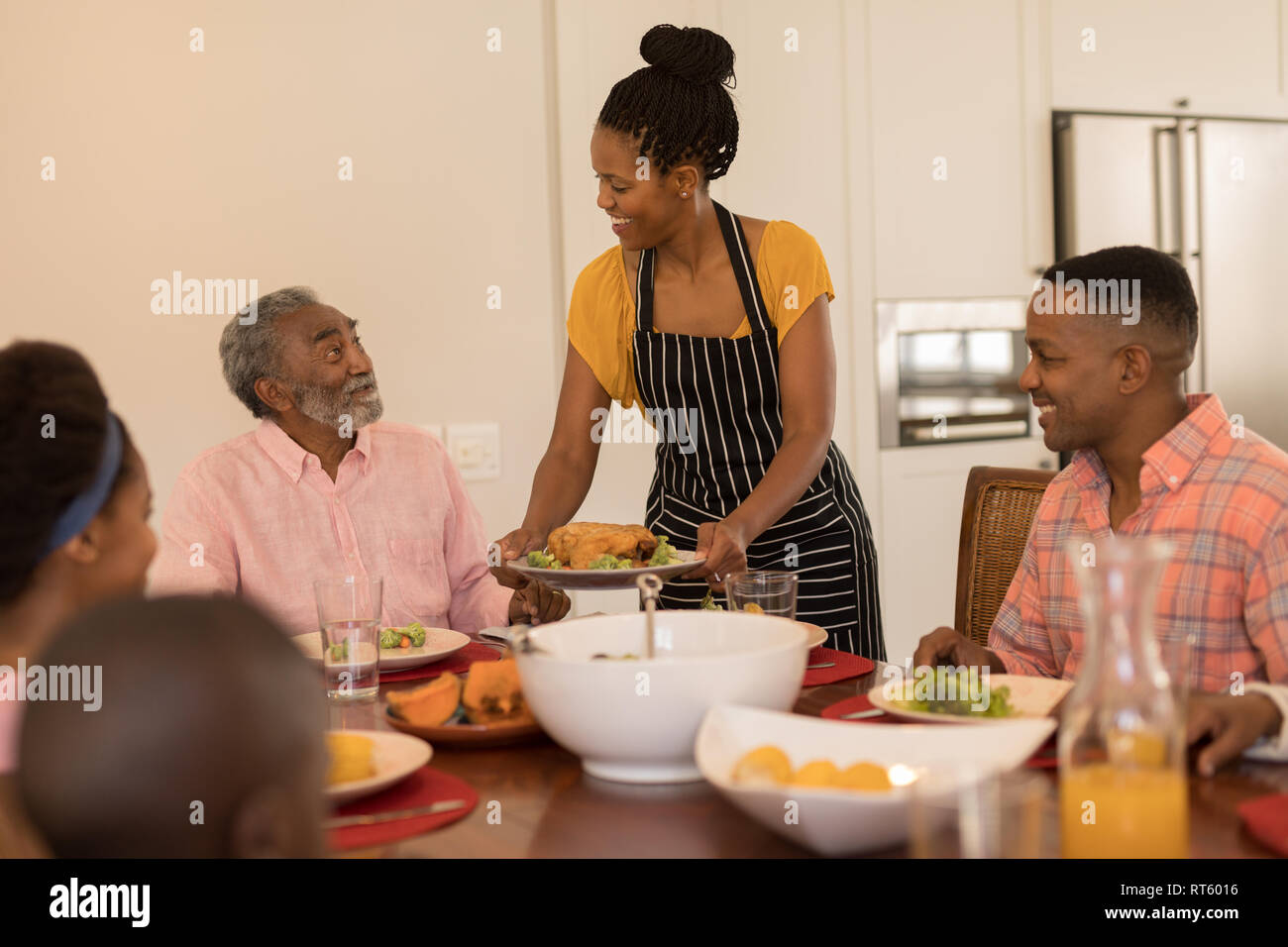 Woman serving food to her family on dining table Stock Photo - Alamy