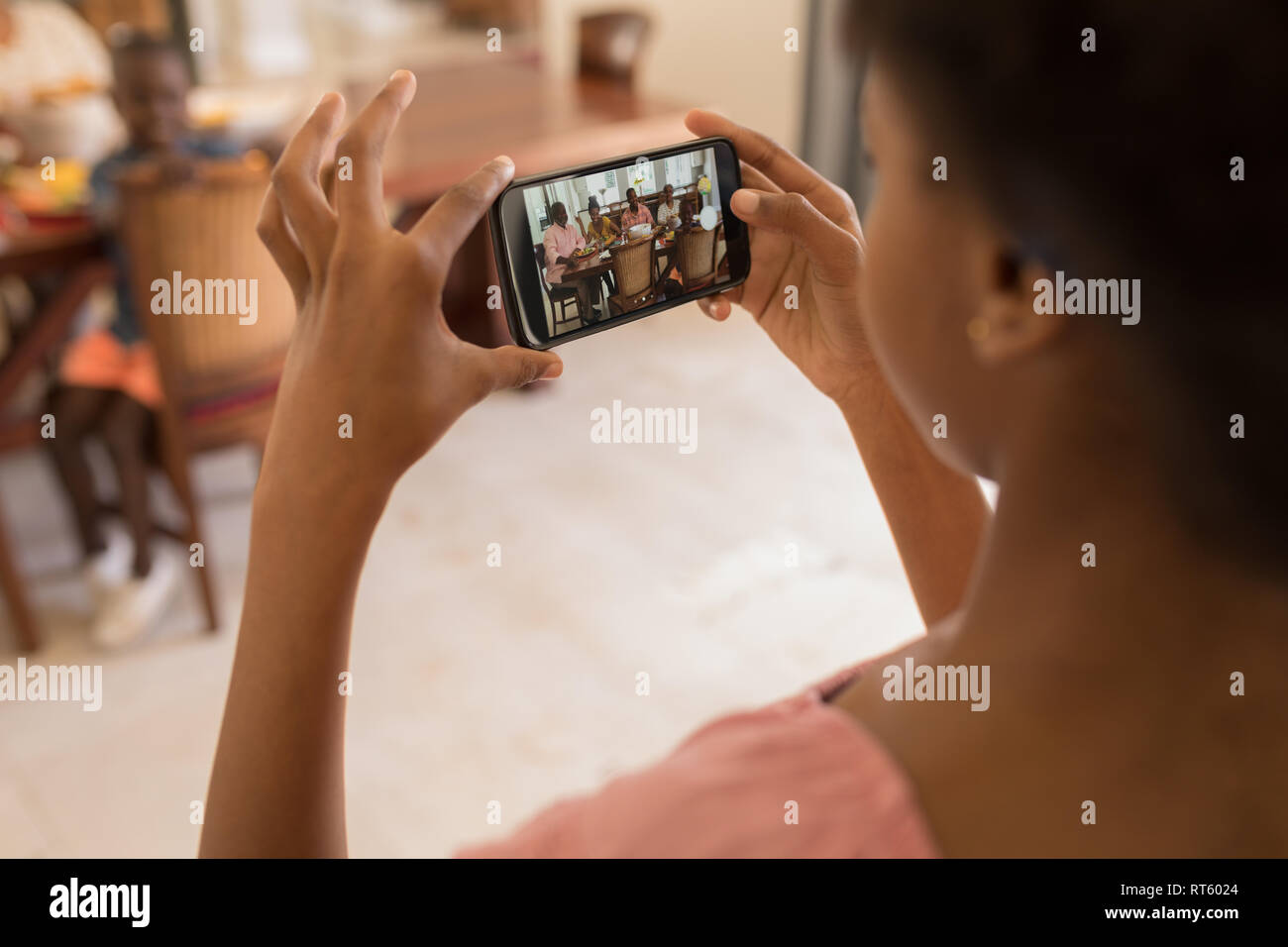 Girl clicking photos of family with mobile phone on dining table Stock ...
