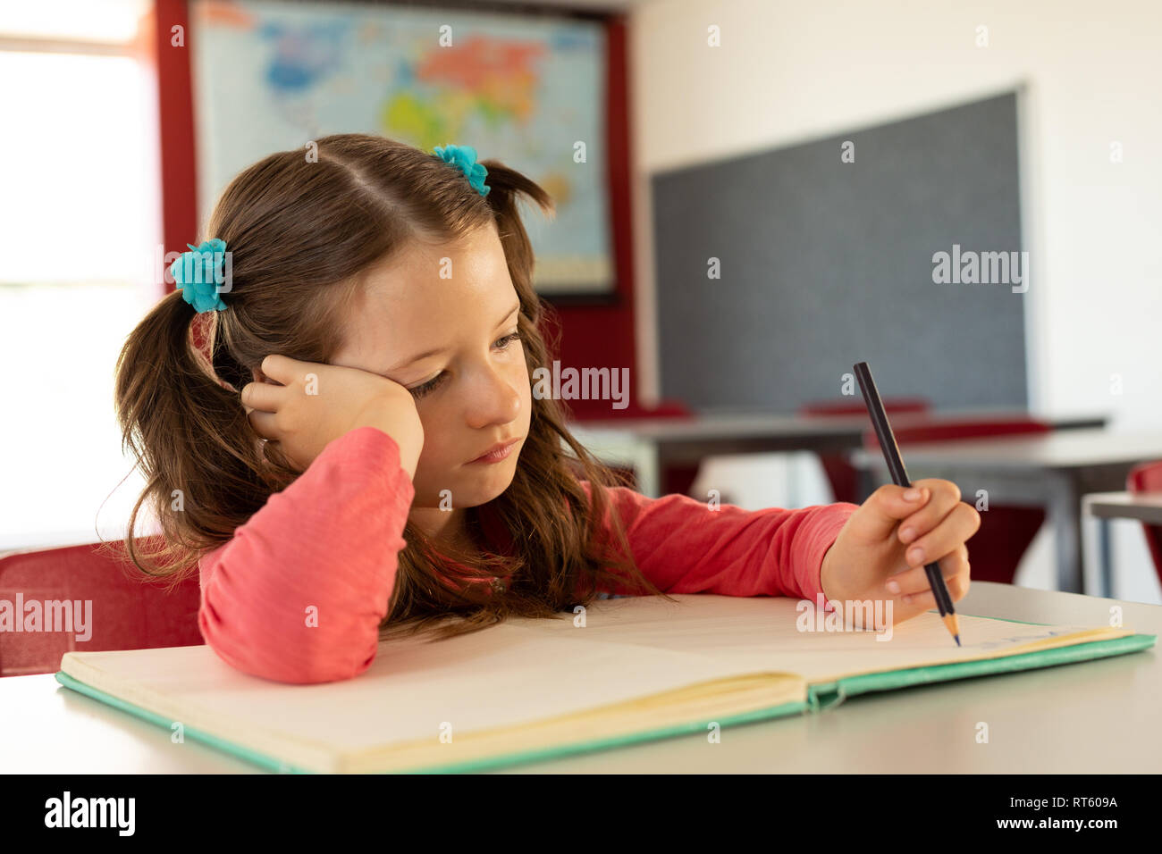 Girl writing on notebook in a classroom Stock Photo - Alamy