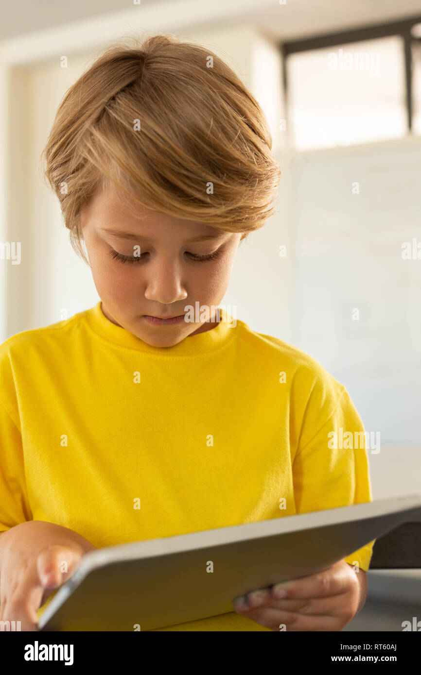 Front view of boy using digital tablet in a classroom Stock Photo - Alamy