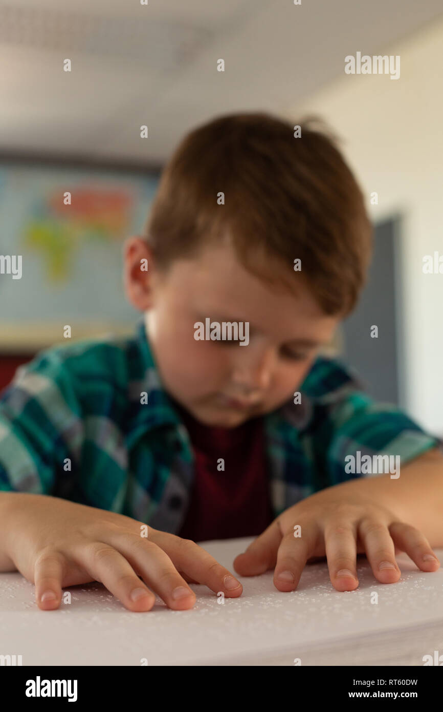 Blind boy reading a braille book at desk in classroom Stock Photo - Alamy